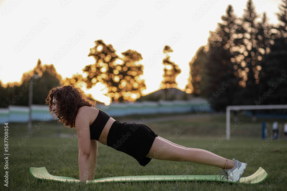 young woman mother goes in for sports gymnastics in summer on a ...