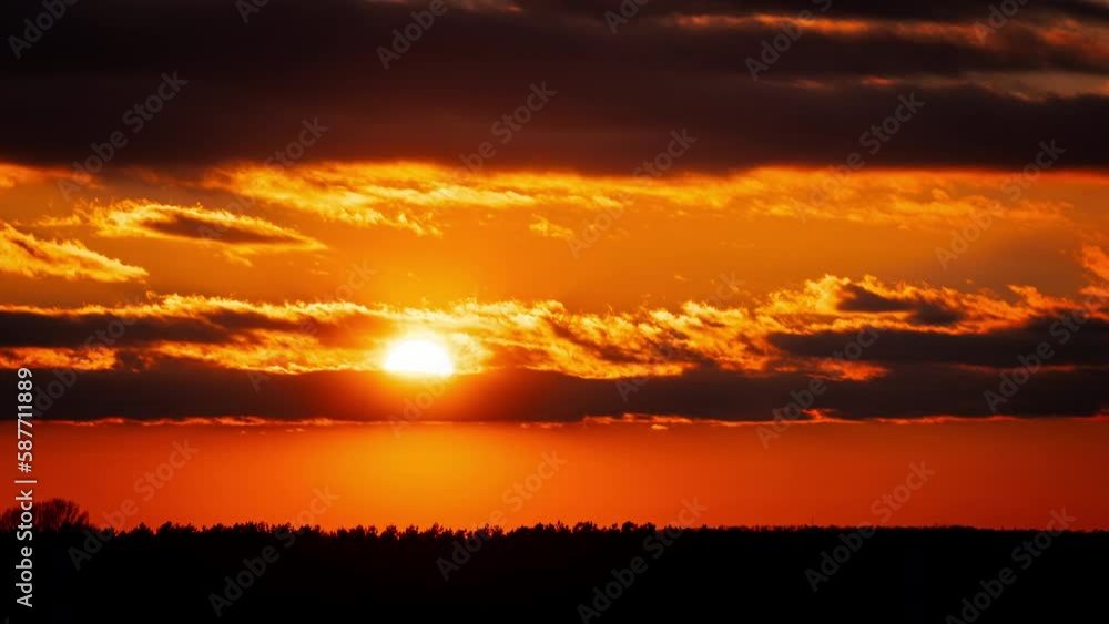 Time lapse bright orange sunset sun sets behind the clouds. The end of ...