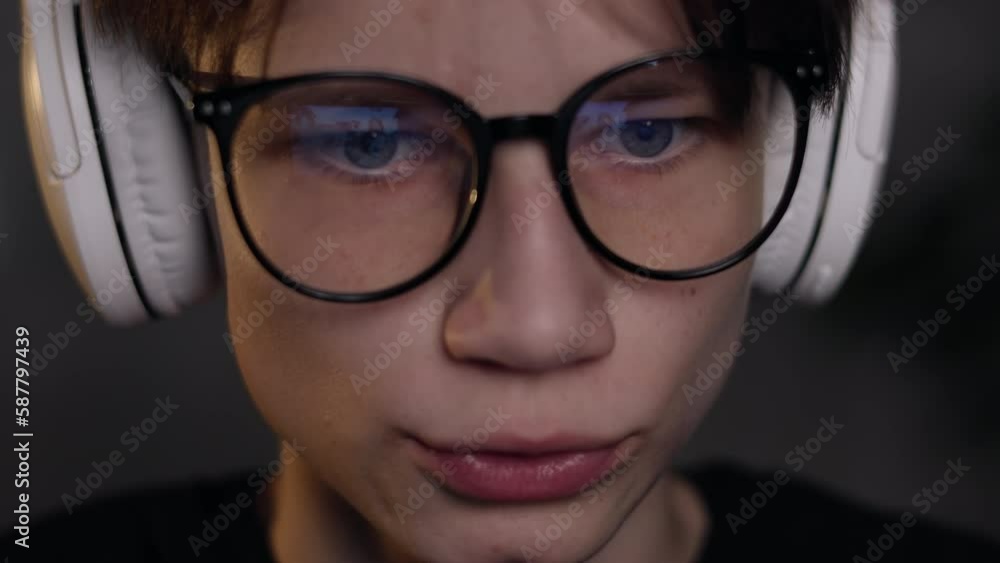 Young gamer man in glasses with screen reflection and headphones ...