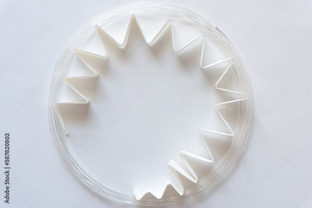 3d printed fan-folded object and clear plastic filament on white paper ...