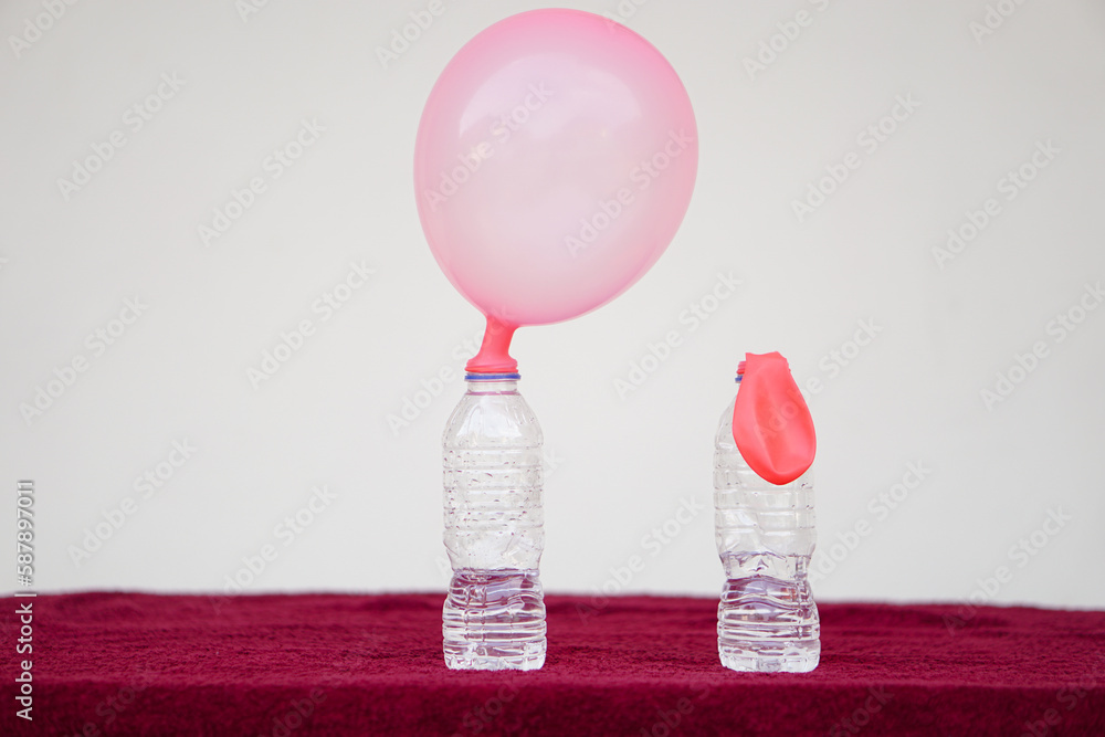 Science experiment , inflated balloons and flat balloon on top of ...