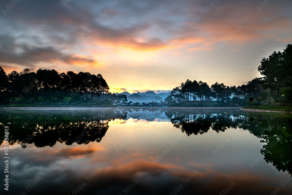 Beautiful dawn on the lake with pink clouds and reflecting sun rays at ...