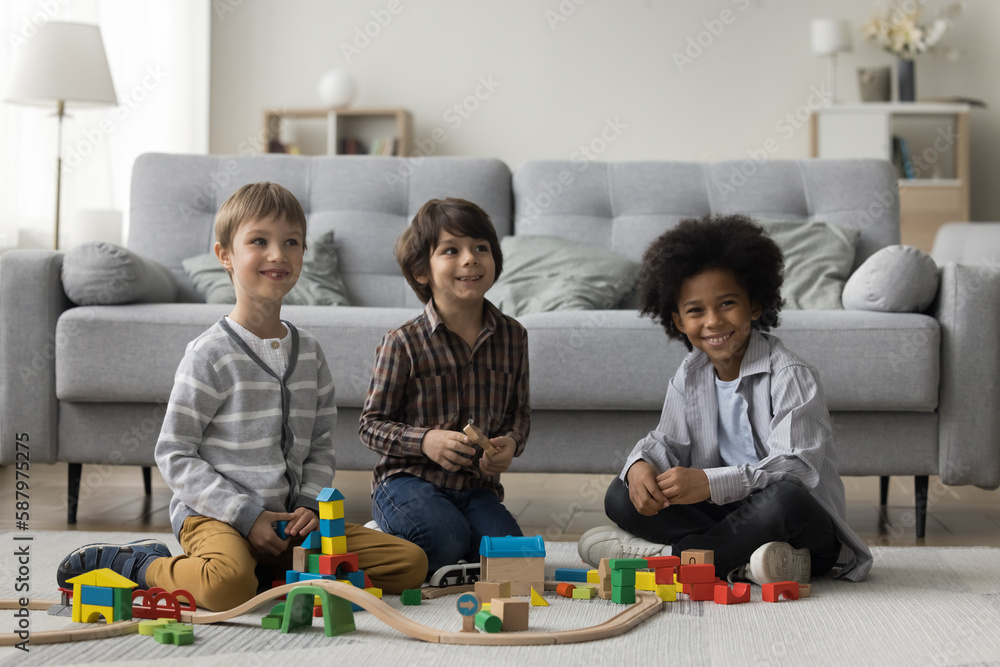 Three happy multiethnic kids playing developing game at cozy home ...