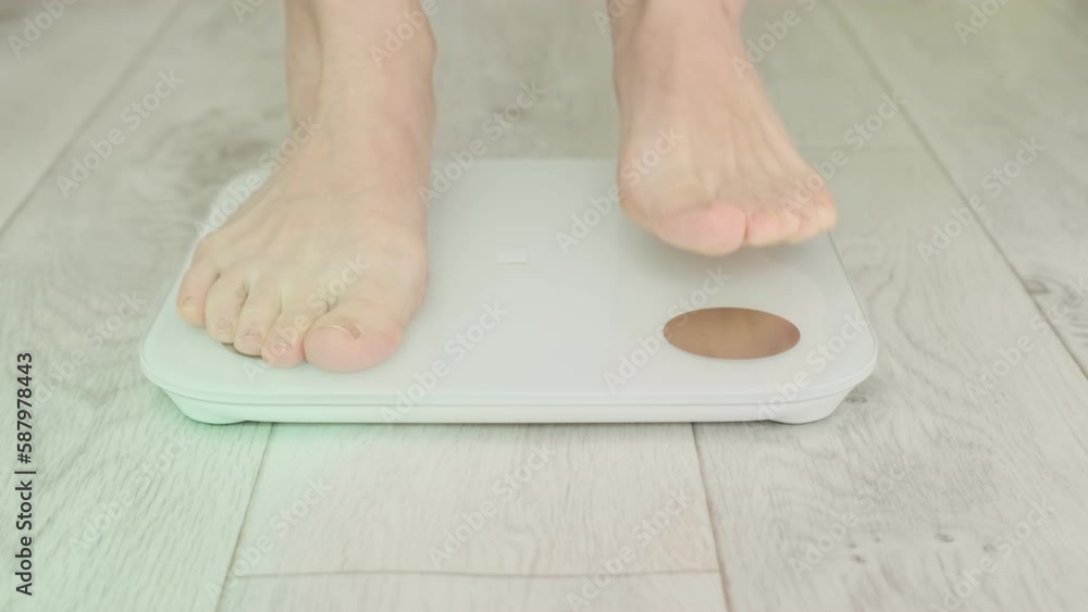 Legs of young girl standing on scale to measure weight. Female bare ...