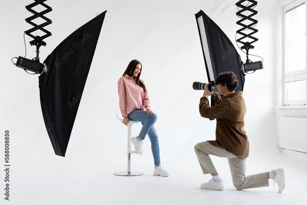 Professional photographer taking picture of young woman, having ...