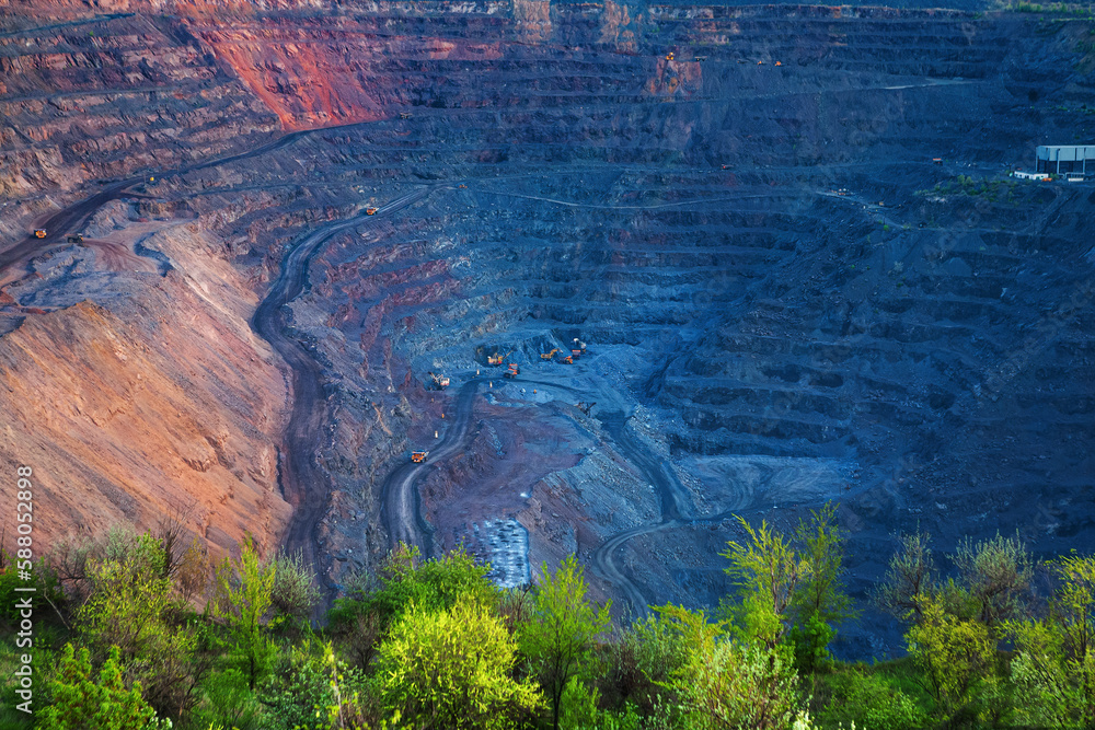 Extraction of iron ore in the evening at the bottom of the open pit ...