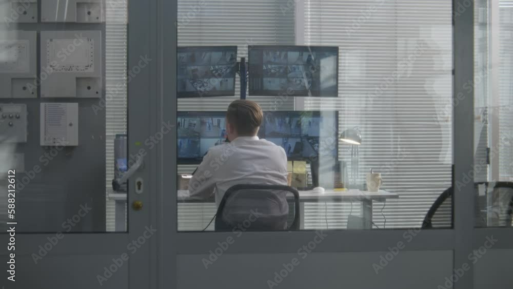 Security operator monitors office CCTV cameras on computers, uses ...
