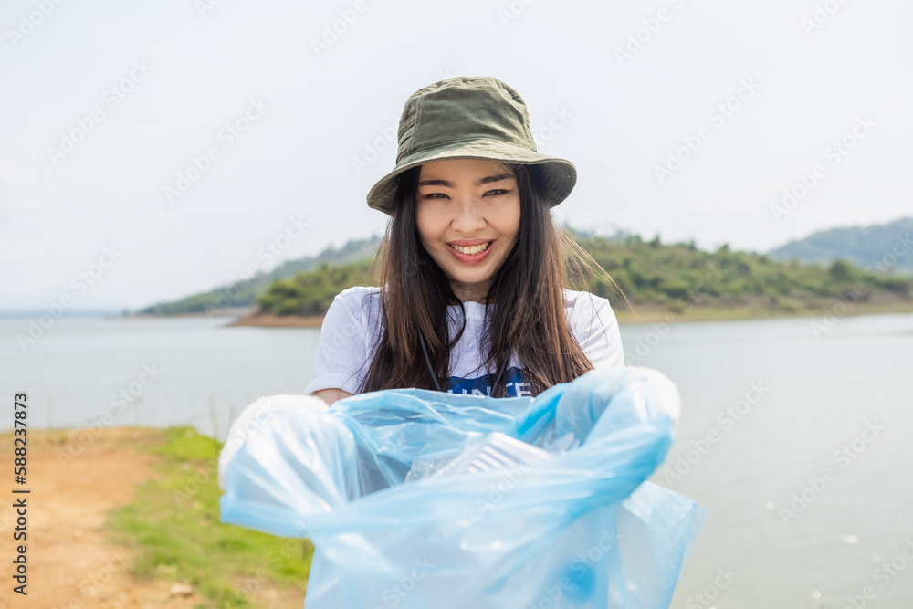 Happy asian female volunteers holding blue garbage bags looking at ...
