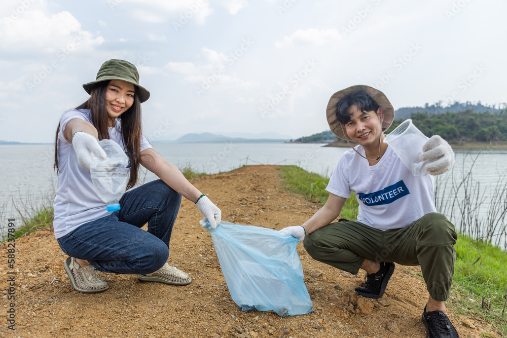 Male and female volunteers collecting garbage, conducting environmental ...