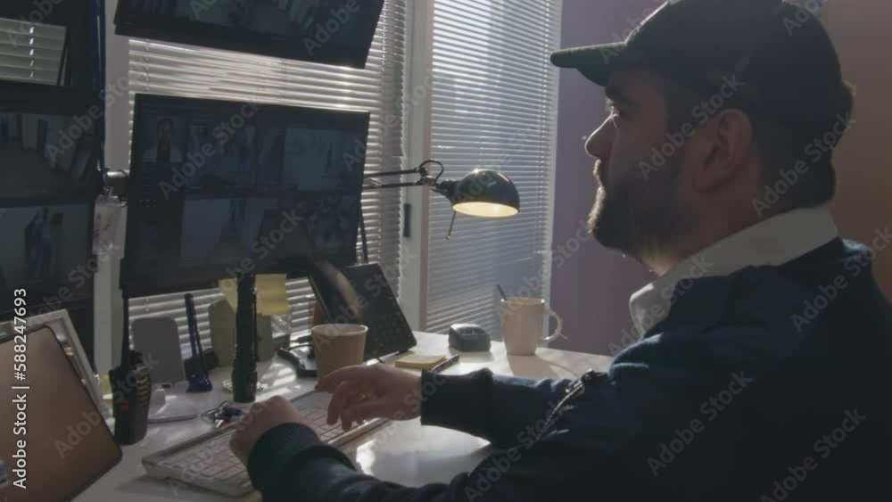 Security guard monitors CCTV cameras in office on computers, uses ...