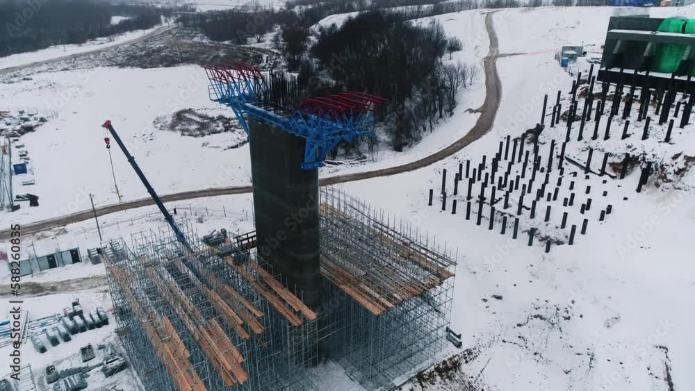Concrete column with metal carcass and scaffolds in snowy valley bird ...