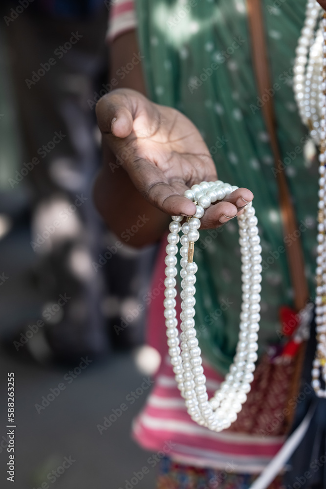 we see a woA close-up of a hand. A woman is holding pearl necklaces in ...