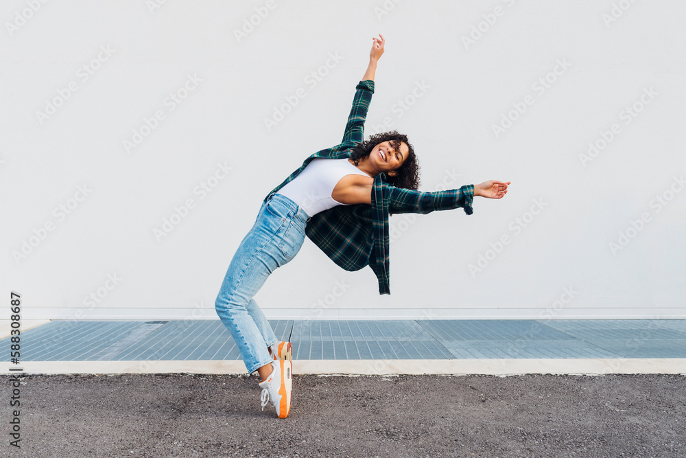 Happy woman dancing and bending over backwards in front of wall Stock ...