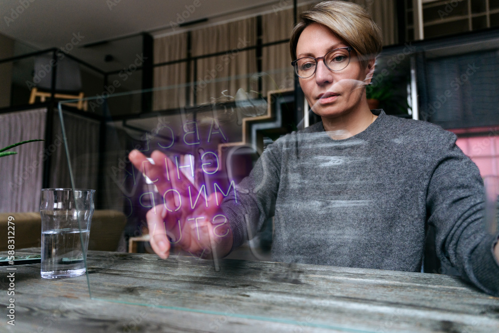 Woman wearing eyeglasses touching transparent glass screen at home ...