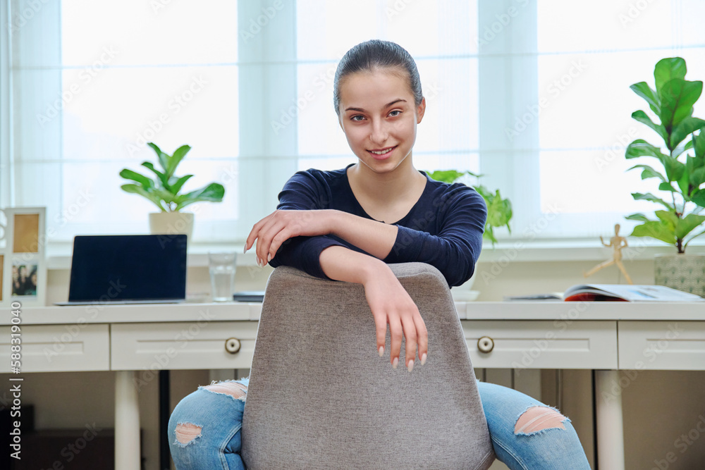 Portrait Of Teenage Smiling Girl Sitting On Chair Home Room Interior