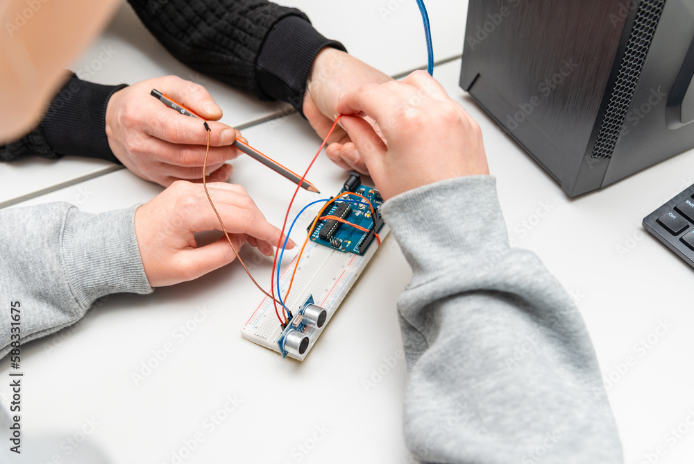 Teacher helping his teen student with diy robot on stem education class ...