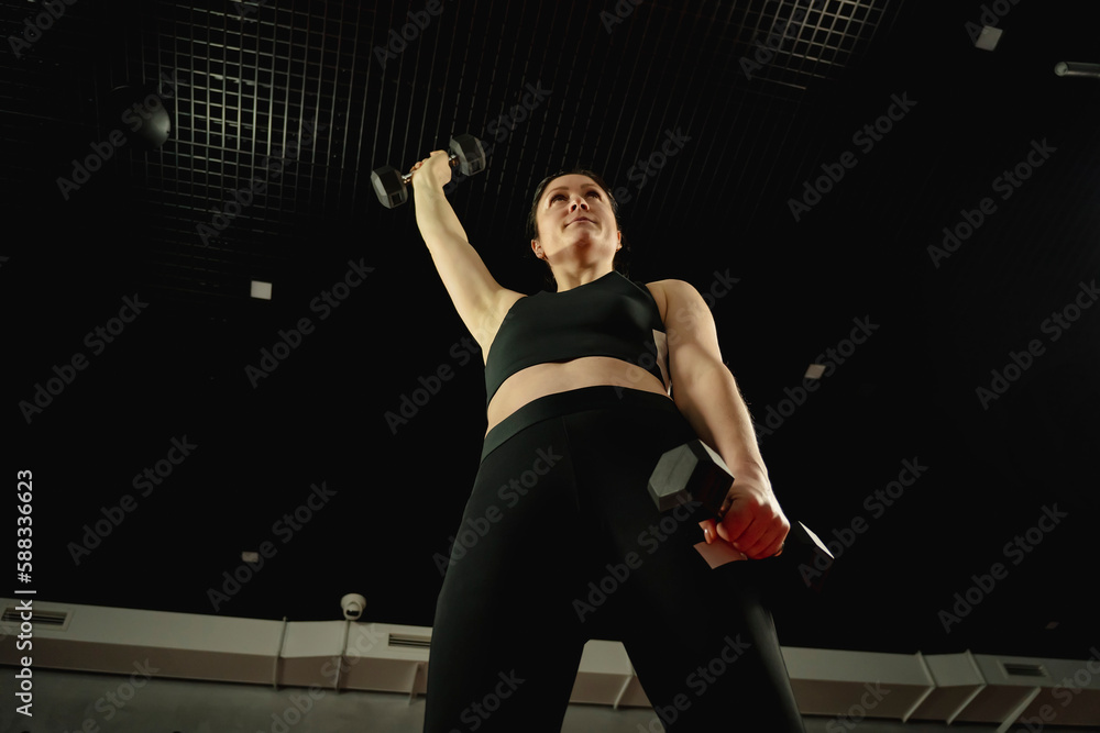 muscular woman lifts dumbbells. Young woman doing fitness. Professional ...