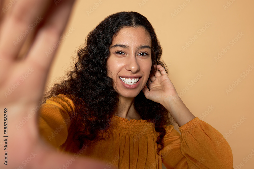 Pretty shy teen latin girl with dark skin touching her long wavy hair ...