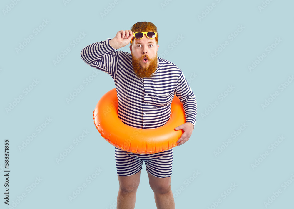 Funny surprised fat man in beach floatie standing isolated on blue ...