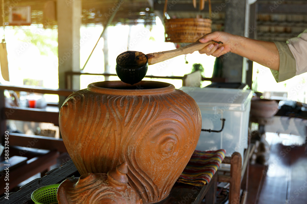 Use a dipper to draw water from a clay pot, which was the home drinking ...