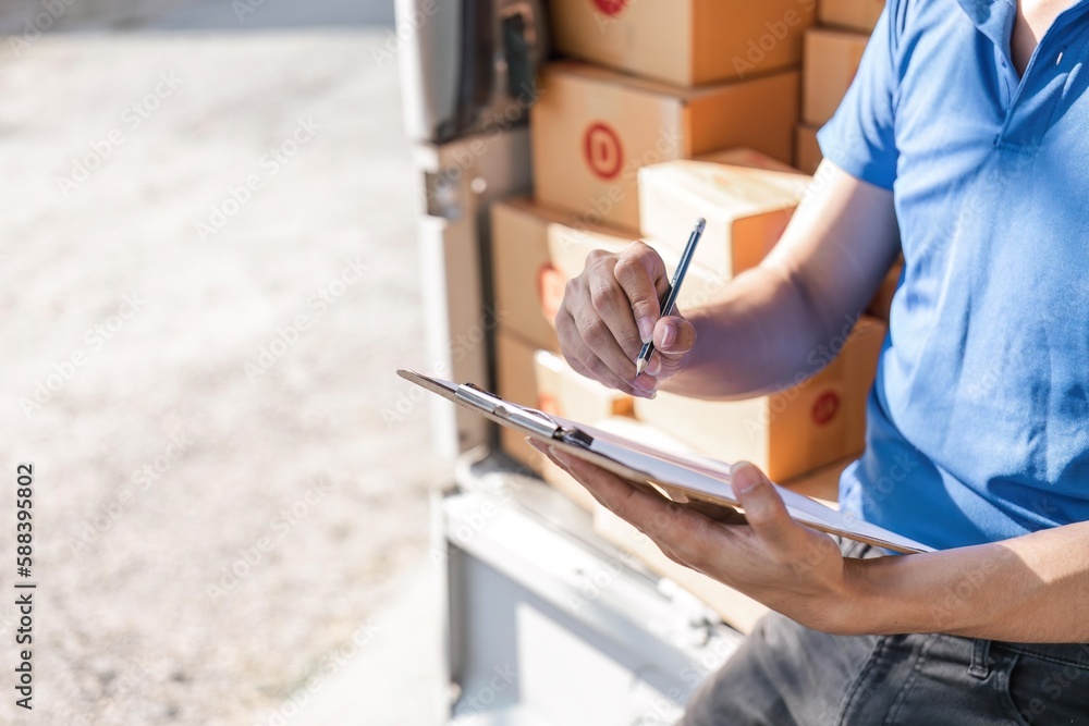 Delivery man signing checklist on clipboard. Male courier writing on ...
