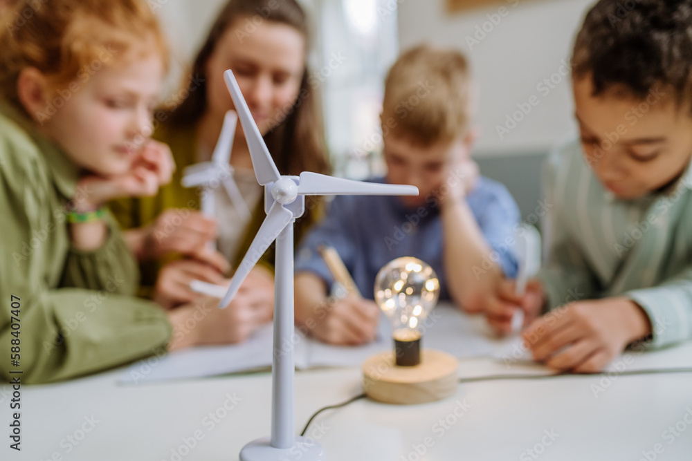 Young teacher with model of wind turbine learning pupils about wind ...