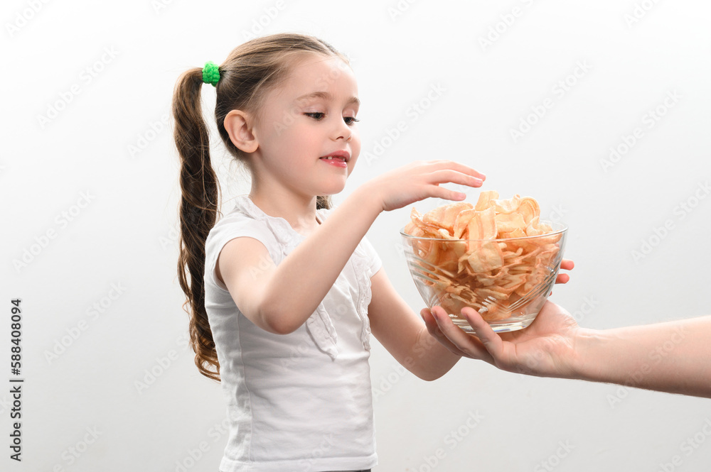 Little girl is given a big bowl of chips snacks with lard, white ...