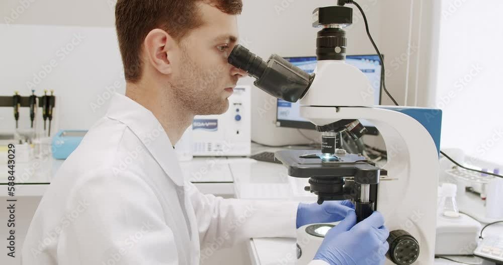 Male doctor using microscope in laboratory. Side view of man in lab ...