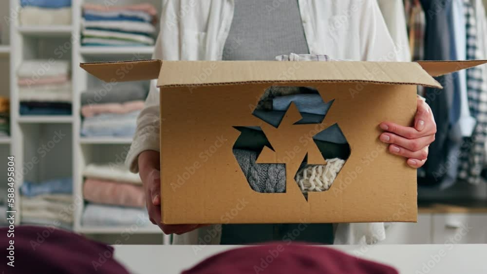 Recycling sign, Volunteer girl collects clothes for recycling in a box ...