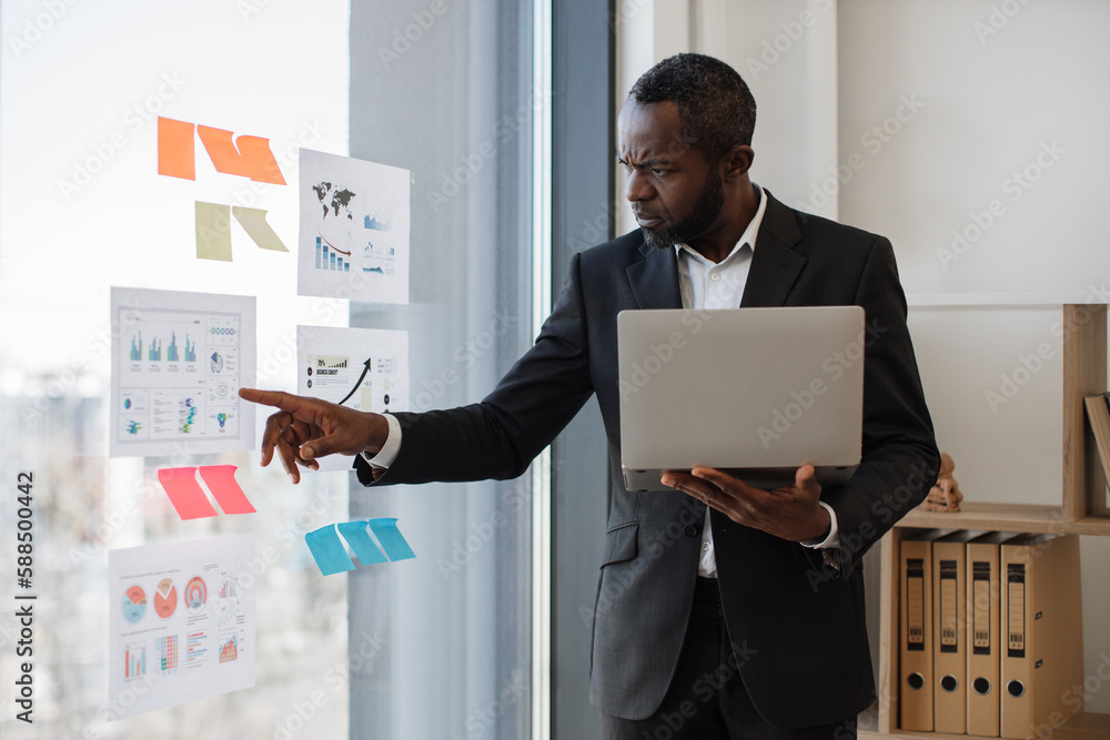 Frowning white-collar worker with wireless computer examining financial ...