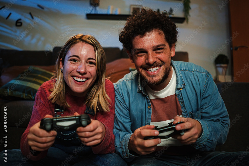 Foto de Young couple having fun plaing video games with a console ...