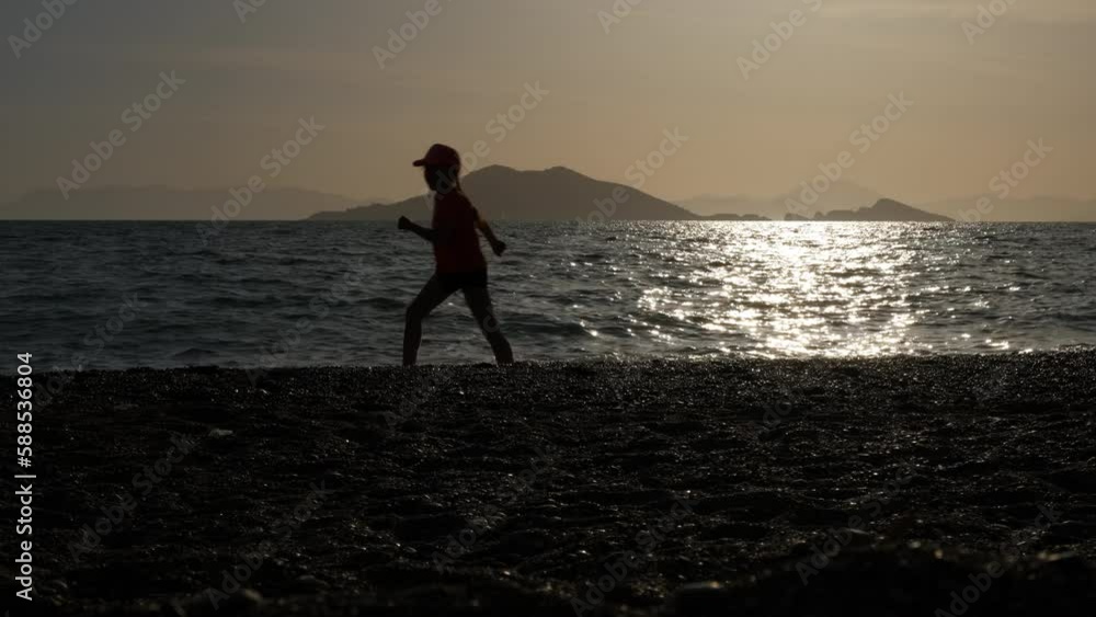 Child silhouette runnig on pebbles bay. A view of little girl ...