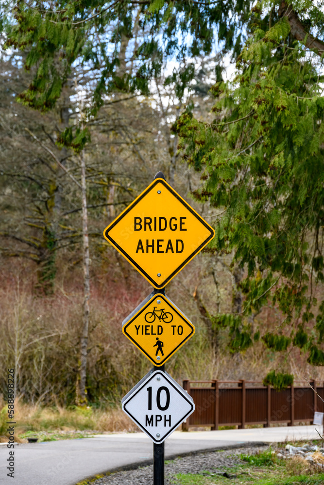 Traffic signs on a multi-use path in a public park, bridge ahead, bikes ...
