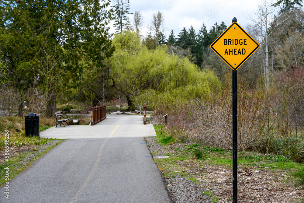Traffic signs on a multi-use path in a public park, bridge ahead, in a ...