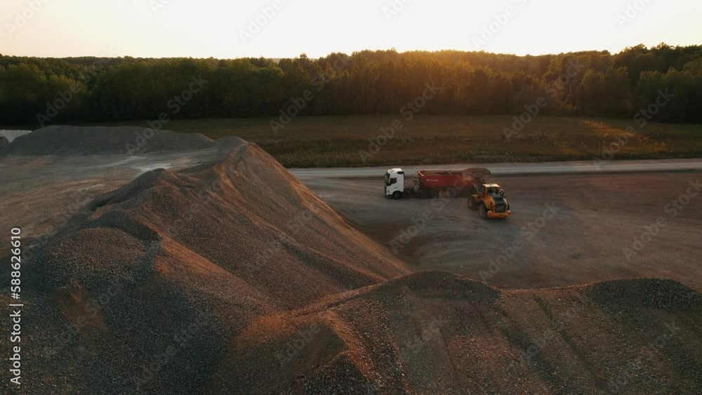 Huge wheel loader with bucket in front load stone in dump truck. Heavy ...