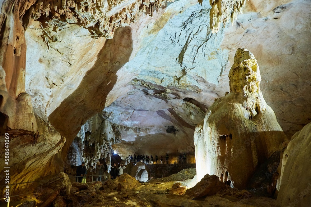 Dark cave view from inside with a lumen. Stalactites and stalagmites ...