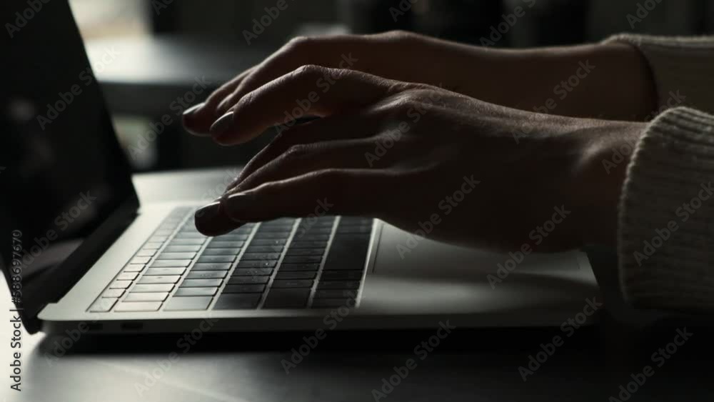 Close up side view of female hands typing on a laptop keyboard ...