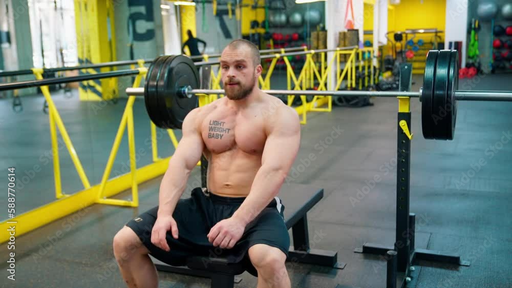 Vidéo Stock Bald bodybuilder exercising in the gym. Raises the barbell ...