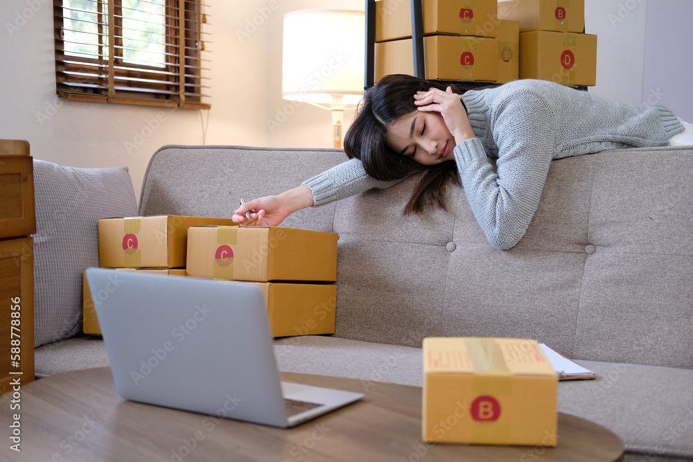 Young beautiful asian woman sitting on sofa in front of laptop. Sleepy ...