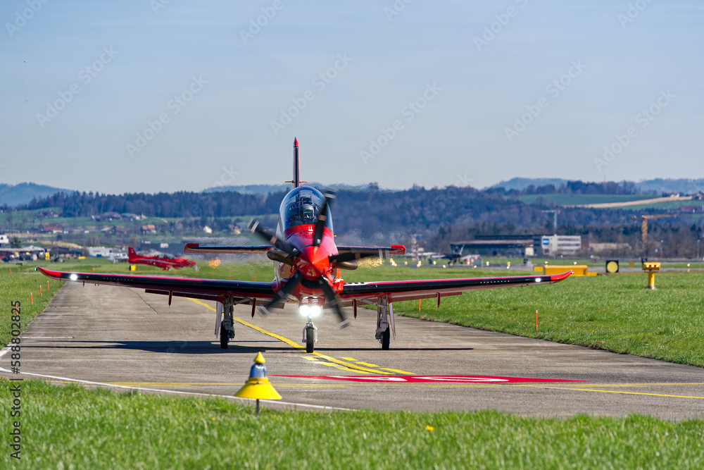 Two red and white Pilatus PC-21 propeller airplanes taxiing to runway ...