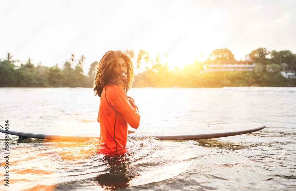 Portrait of black long-haired teen boy with surfboard ready for surfing ...