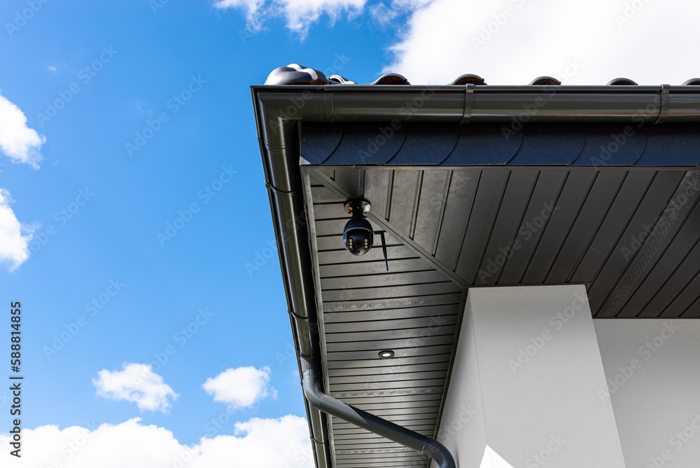 Round wireless camera mounted on the corner of the roof in the soffit ...