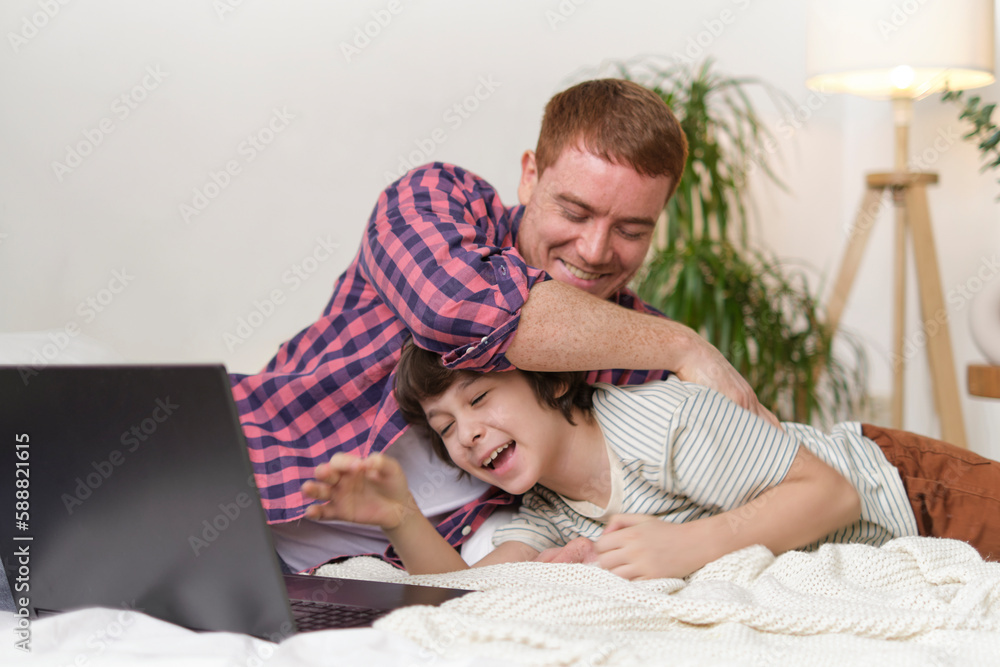 Father tickling son on the bed, sharing laughter and happiness in a ...