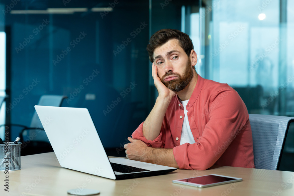 Boring office work. A young man sits in the office at a table with a ...