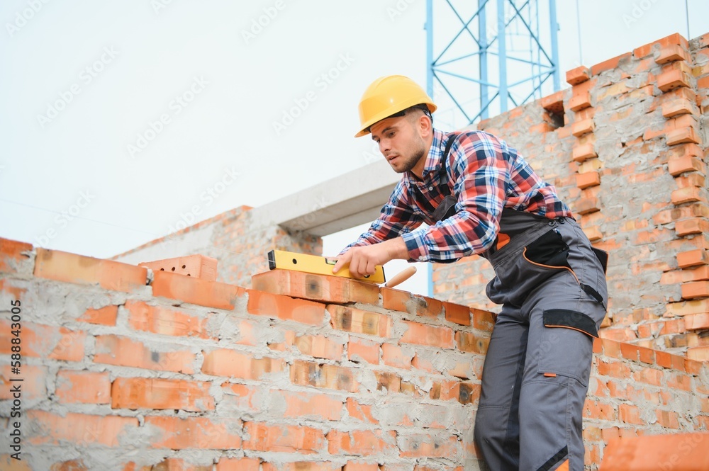 Installing brick wall. Construction worker in uniform and safety ...