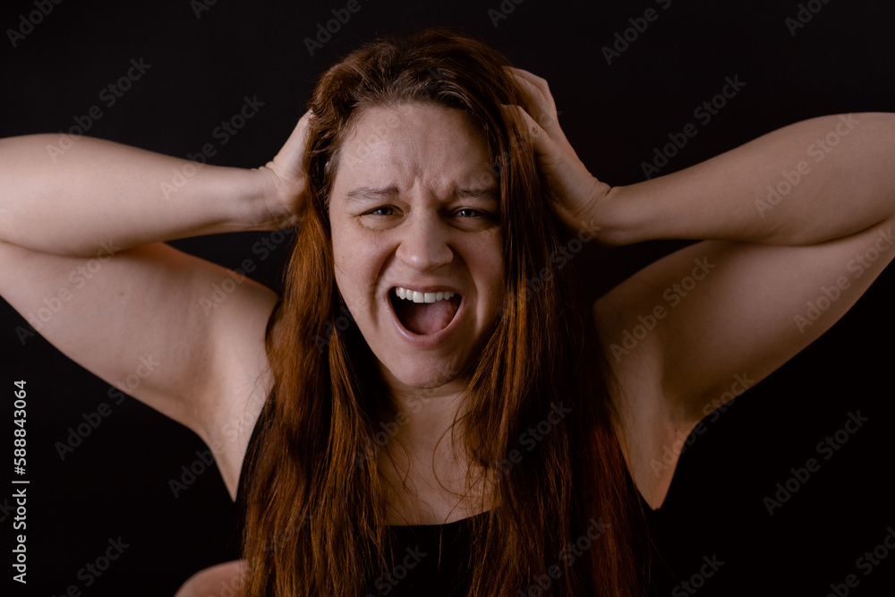Young angry woman rending long hair. Female portrait isolated on black ...