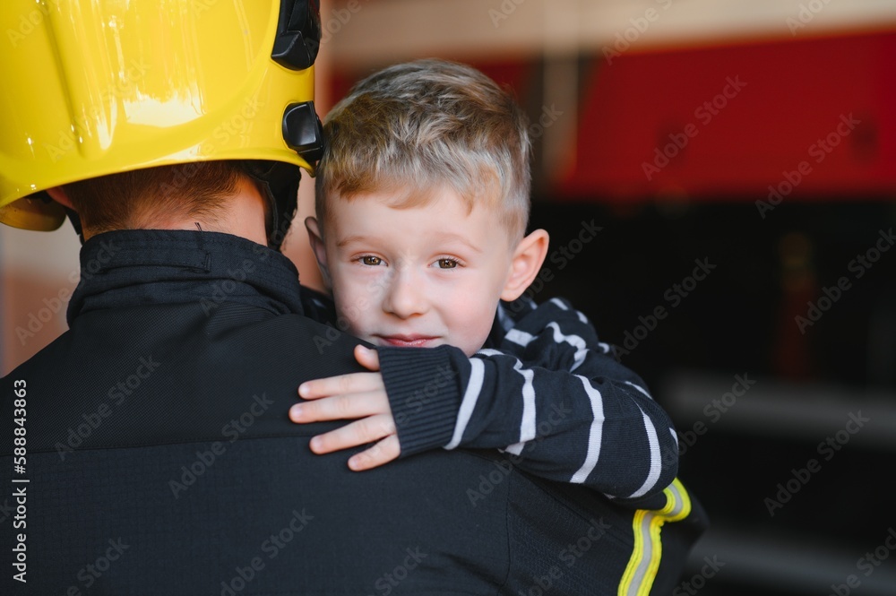 Portrait of rescued little boy with firefighter man standing near fire ...