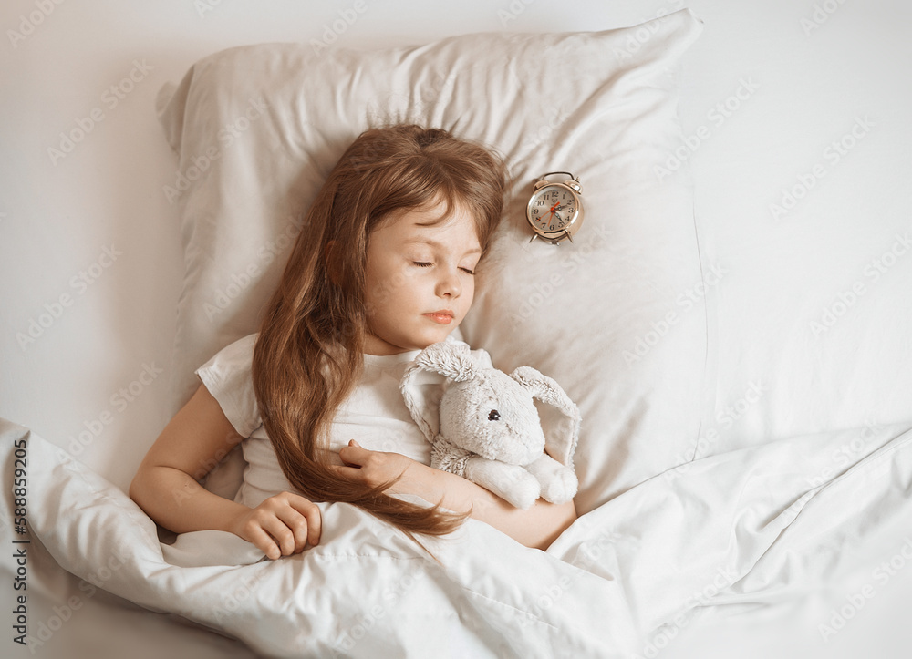 Cute funny cheerful little girl with brown hair sleeping in the white ...