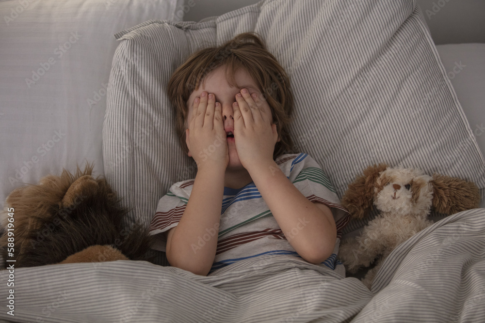 The child was scared. Night terrors in a child. The kid covers his face ...