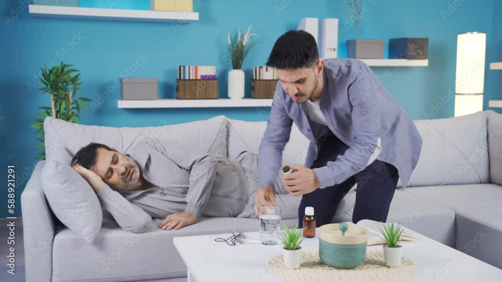 Adult son caring for his sick father at home. The father is sick at ...